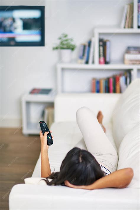 Premium Photo Shes Tuned In Shot Of A Young Woman Watching Tv While