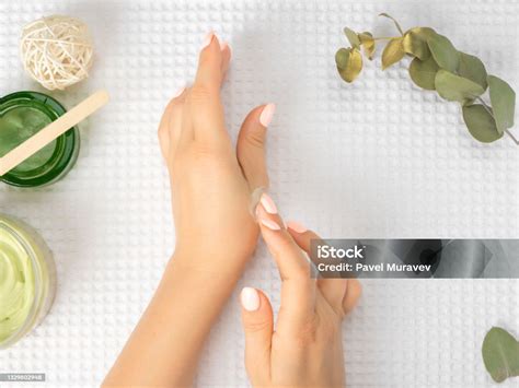 손에 크림을 들고 여자 흰색 수건 배경에 아름다운 여자의 손 손에 신경을 쓰다 깨끗한 피부 손톱에 밝은 분홍색 매니큐어와 아름다운 여성의 손의 클로즈업 이미지 건강관리와