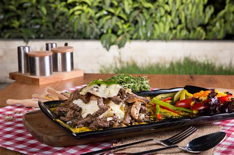 화이트 라이스 리조또 구운된 양고기 고기 녹색 완두콩 삶은 토마토 녹색 피 클 원시 후추와 말린된 백 리 향 봉사 접시에 갈색 삼 베 자루 검은 장식 테이블 천으로 대 한