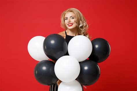 스튜디오에서 밝은 빨간색 배경에 고립 포즈 검은 옷을 입고 미소 젊은 여자 소녀 세인트 발렌타인 데이 생일 휴일 파티 개념 복사 공간을 모의합니다 풍선을 들고 축하합니다