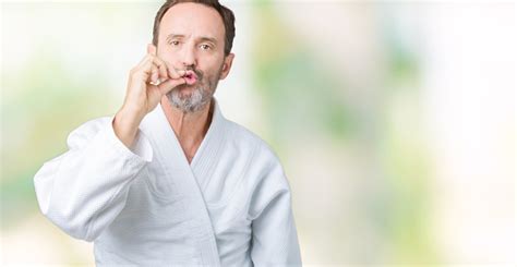 잘생긴 중 년 수석 남자 이상의 기모노 유니폼을 입고 절연 배경 입 그리고 입술 손가락으로 Zip으로 종료 비밀과 침묵 금기 이야기 가라테에 대한 스톡 사진 및 기타 이미지