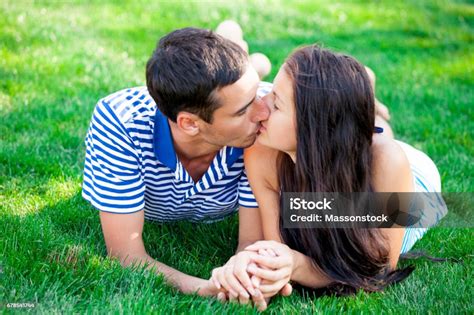 Photo Of Cute Couple Kissing And Lying On The Grass In The Field Stock