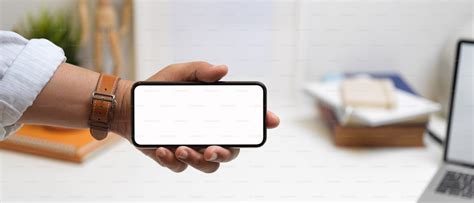 사무실 방에서 클리핑 경로가 있는 수평 스마트폰을 들고 있는 남성 손의 클로즈업 보기 사진 Unsplash의 사진술 이미지