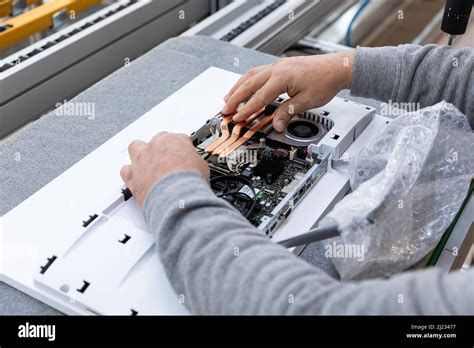 Photo Of Hands Of Man Who Assembles A Computer Monitor System Block On An Conveyor Belt At A