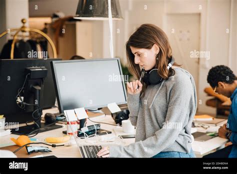 Female Computer Programmer Analyzing Data On Laptop At Desk In Office