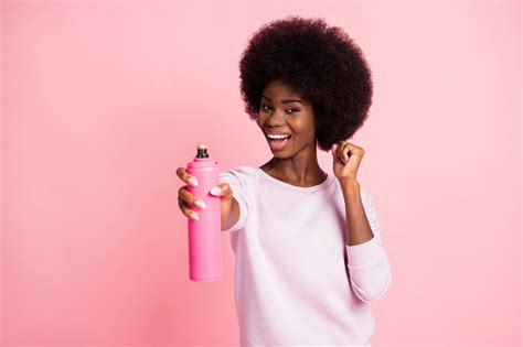 핑크 파스텔 색상 배경 위에 고립 된 고정 스프레이를 적용하는 것을 보여주는 사랑스러운 자신감있는 쾌활한 물결 모양의 머리 소녀의 초상화 쥠에 대한 스톡 사진 및 기타