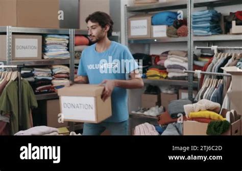 Male Volunteer Sorting And Iterating Clothes For Donations At The
