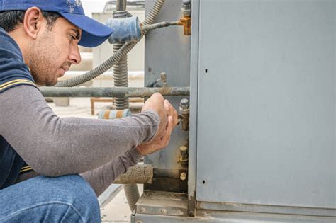 전문 전기 기술자는 건물의 지붕 상단에 있는 공기 조화 기의 무거운 단위를 고정 하 고 파란색 유니폼과 머리 캡을 착용 건설업자에 대한 스톡 사진 및 기타 이미지 Istock