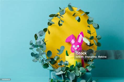 부활절 스탠드는 녹색 잎으로 둘러싸인 달걀 모양의 무대에서 보호 마스크가 있는 분홍색 토끼를 느꼈다 창조적 인 코로나 바이러스