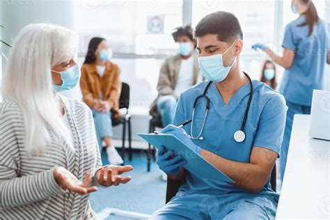 In A Vibrant Clinic A Nurse Communicates With A Senior Patient While