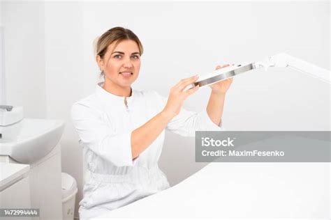 매력적인 여성 미용사는 미용 클리닉의 검사 소파에 램프를 정확하게 고정합니다 건강관리와 의술에 대한 스톡 사진 및 기타 이미지 건강관리와 의술 건강한 생활방식 고객