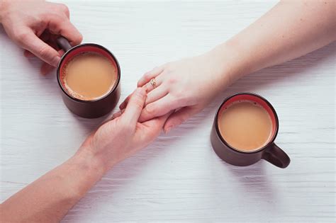 커피 한 잔과 흰색 나무 테이블에 사랑에 부부의 손을 잡고 발렌타인 데이에 컨셉 로맨틱 데이트 상단 보기 플랫 레이 2명에 대한