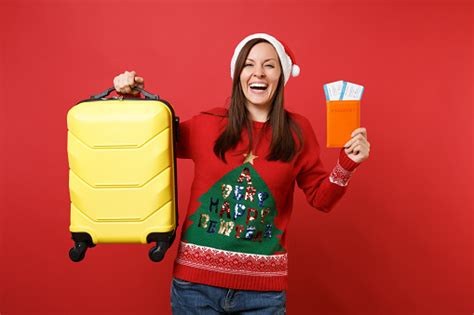 크리스마스 모자 노란색 가방 빨간 배경에 고립 된 여권 보 딩 패스 티켓을 들고 젊은 산타 여자를 웃 고 있다 행복 한 새 해 2019 축 하 휴일 파티 개념입니다 복사