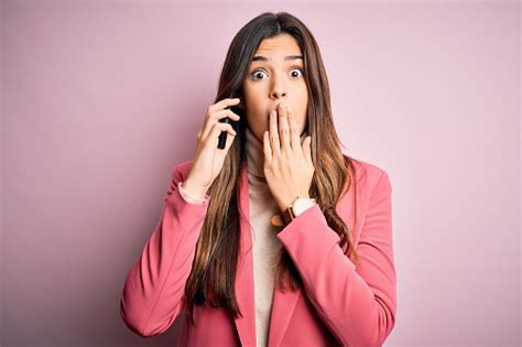 실수 공포의 표정 침묵 비밀 개념에 무서워 손으로 충격을 받은 흰색 배경 커버 입을 통해 스마트 폰에서 이야기하는 대화를 하는 젊은 아름다운 소녀 가리기에 대한 스톡 사진