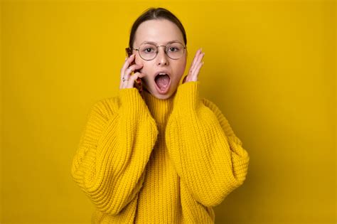 놀란 갈색 머리 여자가 휴대 전화를 들고 노란색 스웨터를 입고 Yelllow 배경에 고립 된 클로즈업 사진 20 29세에 대한 스톡 사진 및 기타 이미지 Istock