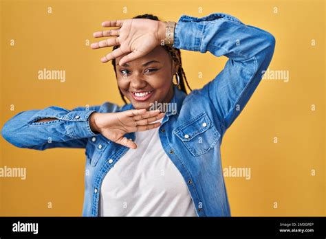 African American Woman With Braids Standing Over Yellow Background