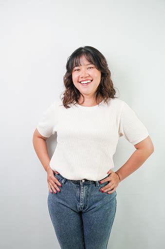 흰 셔츠를 입고 물결 모양의 머리를 한 아름 다운 젊은 아시아 여성이 흰색 배경 위에 고립 된 자신감있는 제스처를 보여주고 있습니다 아시아에 대한 스톡 사진 및 기타 이미지