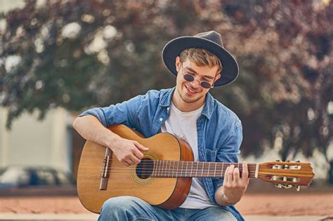 기타를 연주하는 청년 모자를 가진 세련된 힙스터 남자는 음악과 휴일을 즐긴다 기타 현악기에 대한 스톡 사진 및 기타 이미지