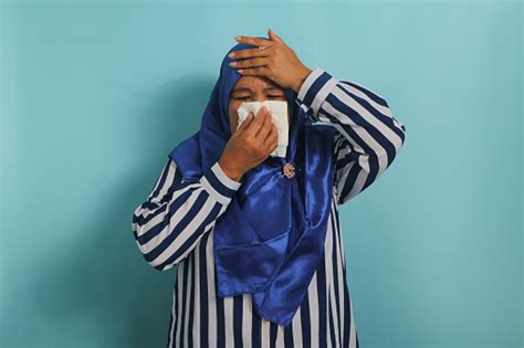 독감에 걸린 아시아 여성이 파란 히잡을 입고 재채기를 하고 코를 푼다 의료 개념입니다 50 54세에 대한 스톡 사진 및 기타 이미지 50 54세 감기와 독감 개념