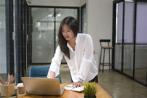 젊은 여성 회사원이 사무실에 서서 노트북 컴퓨터에 타이핑을 하고 있다 사진 Unsplash의 태국 이미지