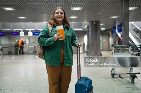 공항 터미널에서 수하물을 들고 걷는 행복한 미소 짓는 여성 티켓이 든 여권을 들고 출발 출발 중 여행 가방을 들고 있는 쾌활한 여성 Brand Name Smart Phone