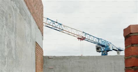벽돌과 콘크리트 패널로 구성된 미완성 아파트 블록의 일부와 건설 지역에서 작동하는 자동 타워 크레인 사진 Unsplash의 사업 이미지