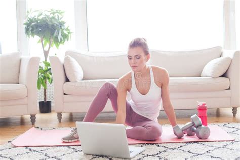 Cute Woman Doing Exercise And Watching Online Tutorials On Laptop Training In Living Room Stock
