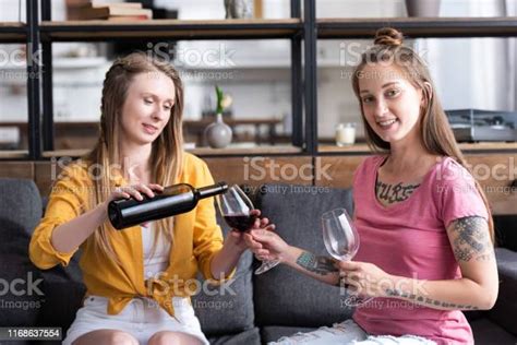 두 레즈비언 들고 와인 잔 과 붓는 와인 동안 앉아 에 소파 에 거실 2명에 대한 스톡 사진 및 기타 이미지 2명 가정의 방 거실 Istock