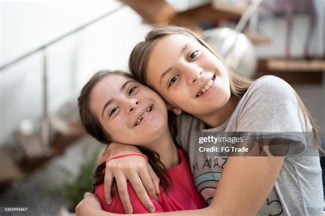 Portrait Of Sisters Embracing At Home Girl With Special Needs High Res