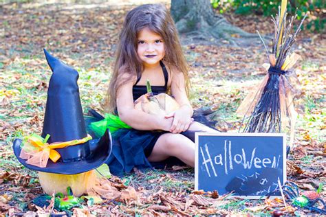 할로윈 휴가를위한 마녀 의상을 입은 소녀 비문이있는 플라 카드 할로윈 풀밭에 앉아있는 소녀 10월에 대한 스톡 사진 및 기타 이미지 Istock