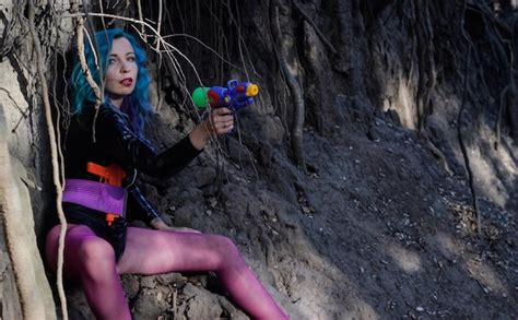 Portrait Of Woman Holding Squirt Gun While Sitting On Field Premium Photo