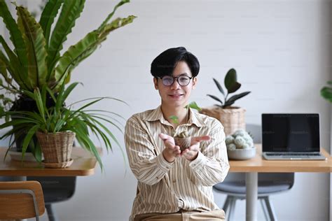 성공적인 중소기업 기업가는 꽃집에 앉아 작은 화분을 들고 있습니다 사진 Unsplash의 실내 이미지