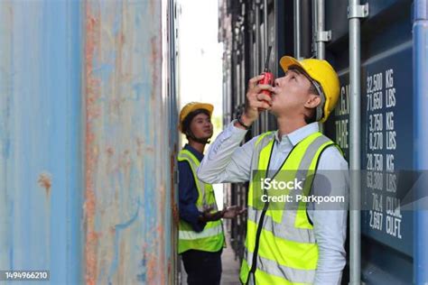 스마트 휴대 전화와 워키 토키 무선 제어 적재 컨테이너 상자를 사용하는 감독 안전모를 쓴 작업자가 컨테이너 화물 현장에서 일하고 산업용 컨테이너 화물 화물선을 점검하고 있다