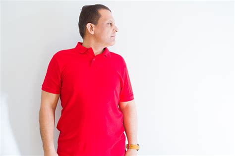 흰 벽 위에 빨간 T 셔츠를 입고 중간 나이 남자는 자신감 있는 미소로 자연 스러운 얼굴로 프로 파일 포즈를 취하십시오 T 셔츠에 대한 스톡 사진 및 기타 이미지 Istock