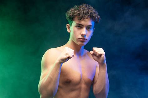 벌거 벗은 몸통을 가진 진지한 수심에 찬 십대 소년 연기가 자욱한 파란색 배경에 싸우는 몸 14 15 살에 대한 스톡 사진 및