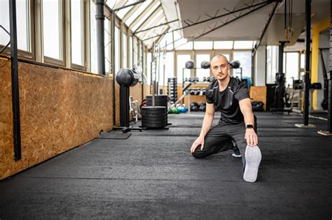 피트니스와 근력 운동에 중점을 둔 현대적인 체육관 환경에서 스트레칭을 하면서 유연성을 보여주는 젊은이 개선에 대한 스톡 사진 및 기타 이미지 Istock