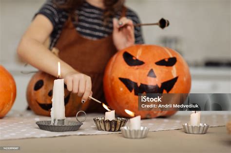 아이 소녀는 할로윈을 위해 촛불을 켭니다 아이가 만든 얼굴로 호박을 조각 한 마녀 의상을 입은 어린 소녀 할로윈을 준비하는 행복한 가족 선택적 초점 10월에 대한 스톡 사진