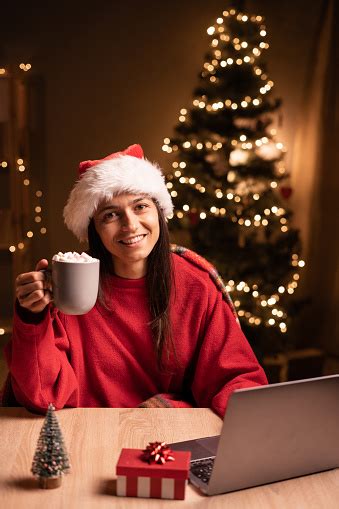 산타클로스 모자를 쓴 여자는 책상에 앉아 컴퓨터를 보며 웃고 있다 12월에 대한 스톡 사진 및 기타 이미지 12월 30 34세 개성 개념 Istock