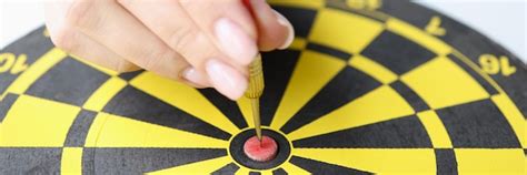Premium Photo Closeup Of Female Hand Put Red Dart Arrow Right In Center Of Dartboard Hit Goal