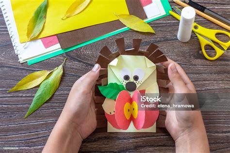 아이는 종이 인사말 카드의 배낭과 나무 테이블에 사과와 엽서 고슴도치를 들고있다 손으로 만든 어린이의 창의력 수공예품 어린이를 위한 공예품 프로젝트 9월에 대한 스톡 사진