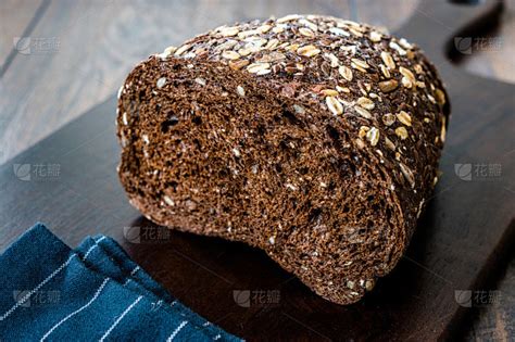 麦芽面包片与燕麦和亚麻籽在深色木板上。