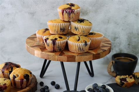 블루베리 대리석 효과 배경으로 둘러싸인 회색 모슬린과 커피 머그잔 외에 종이 케이크 케이스에 수제 블루베리 머핀이 쌓여 있는