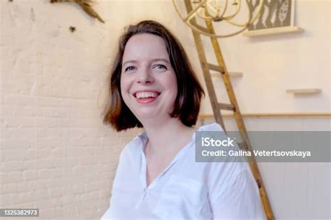 흰색 벽돌 벽 배경에 흰색 셔츠에 어깨 길이 어두운 머리를 가진 젊은 여성의 초상화 여자에 대한 스톡 사진 및 기타 이미지 여자 유머 재정 고문 Istock