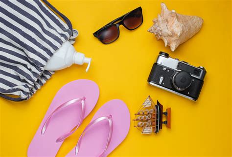 여름 정물 해변 액세서리 노란색 종이 배경에 유행 핑크 플립 플롭 가방 복고풍 카메라 자외선 차단 병 선글라스 조개 플랫 레이 공간을 복사합니다 맨 위 보기 가방에 대한