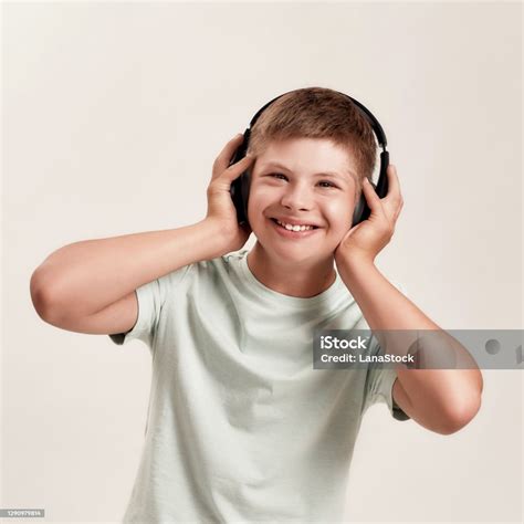 헤드폰에서 다운 증후군을 가진 행복한 장애인 소년의 초상화는 음악을 듣고 흰색 배경 위에 고립 된 서있는 동안 카메라에서 미소 스튜디오 촬영에 대한 스톡 사진 및 기타