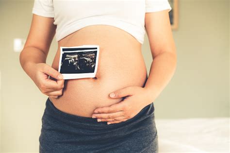 임신 한 여자는 그녀의 아이를 돌보는 동안 집에서 행복 느낌 임신 뱃속에서 아기를 안고 있는 어머니를 기다리는 젊은 출산 태아 관리 및 여성 임신 개념 개념에 대한 스톡