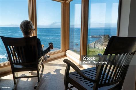 바다 를 향한 빈 흔들 의자 옆에 앉아 있는 한 여성 해변에 대한 스톡 사진 및 기타 이미지 해변 흔들의자 한 명의 여자만 Istock