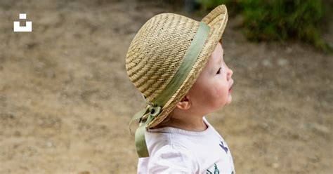 흰색 티셔츠와 노란색 바지를 입은 소녀가 갈색 짠 모자를 쓰고 있다 사진 Unsplash의 무료 링비 이미지