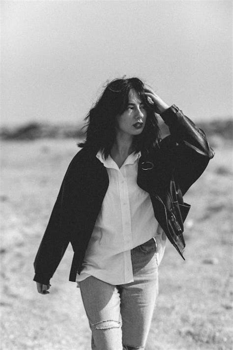 찢어진 청바지와 검은 가죽 재킷을 입고 포즈를 취하는 갈색 머리 여성 · 무료 스톡 사진