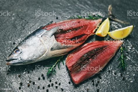 허브 향신료 로즈마리와 레몬 스테이크 또는 샐러드 슬라이스 신선한 생선 필레 검은 접시 배경에 생선 해산물 롱 테일 참치 요리 음식을위한 동부 작은 참치 필레 재료 날것에